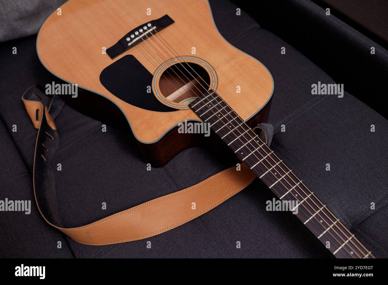 Beautiful six-string acoustic guitar, wood body, on sofa in studio ...