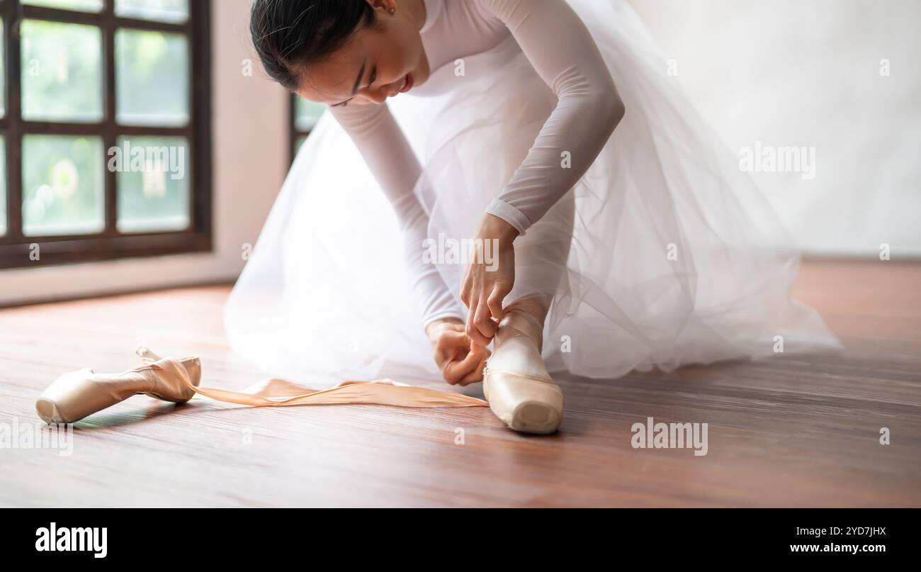 Ballerina in ballet shoes. Asian girlÂ tying ribbons of toe shoes ...
