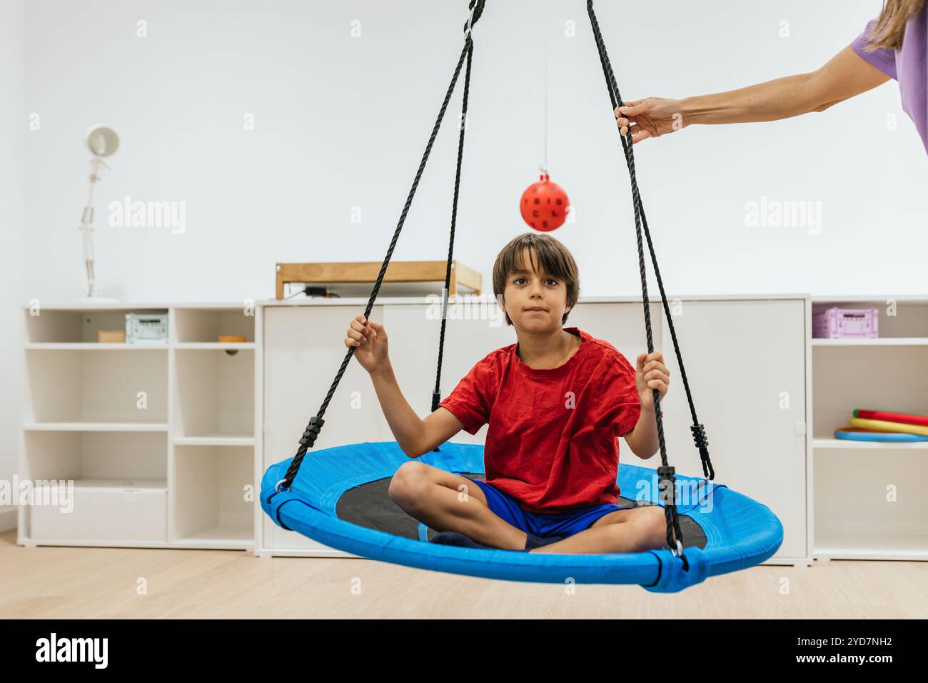 Child doing therapy exercises on swing using marsden ball in clinic ...
