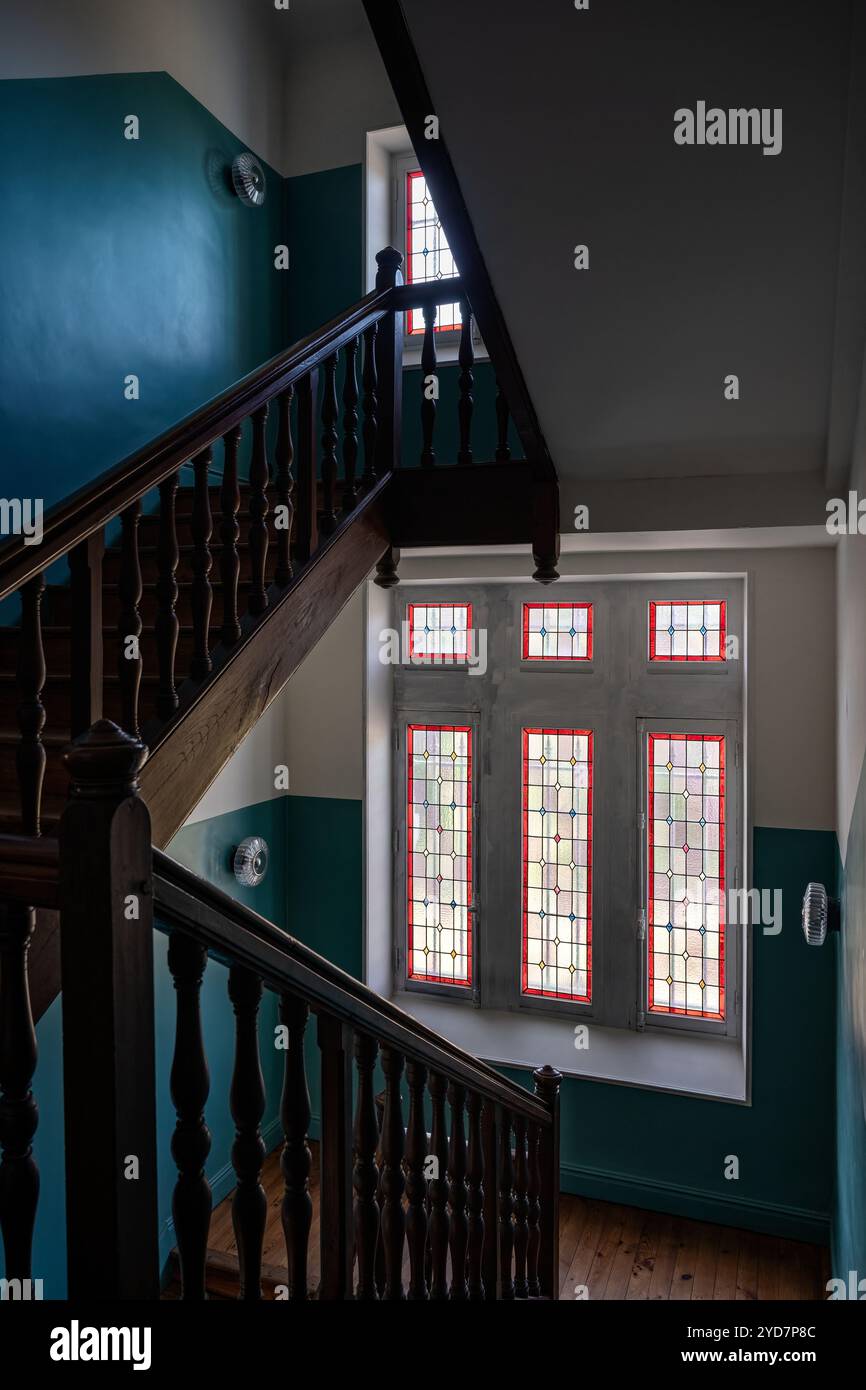 Teal staircase with wooden banister and stained glass windows in luxury ...