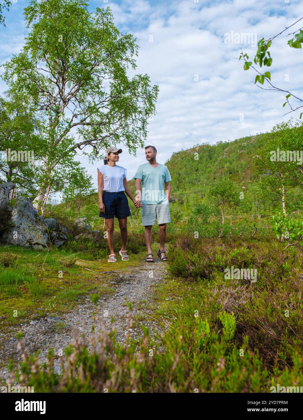 A couple walks hand-in-hand along a path in a Norwegian forest ...