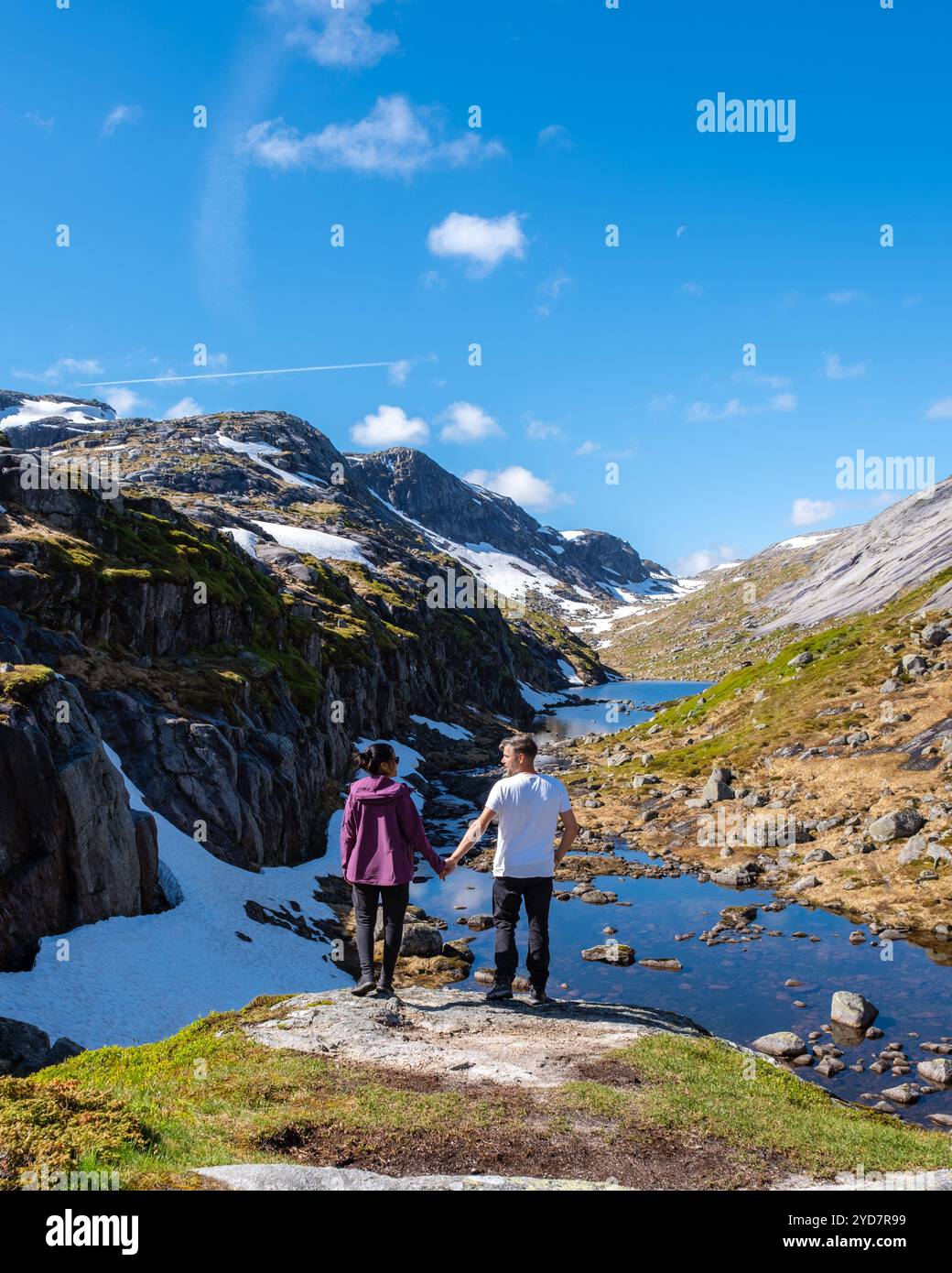 A couple stands hand-in-hand, overlooking a serene mountain valley in ...