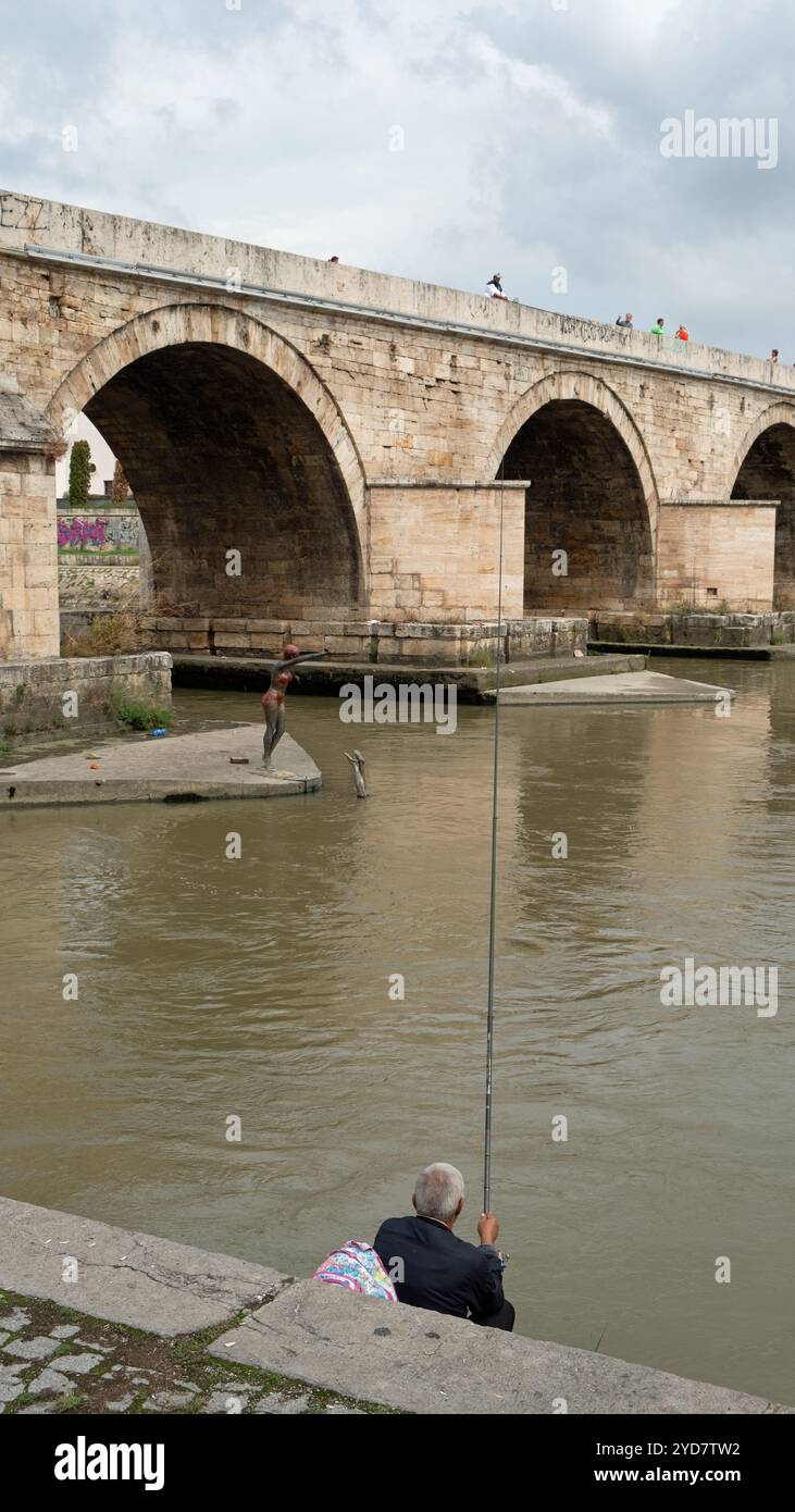 Man fishing by the Stone Bridge, Skopje, Republic of North Macedonia ...