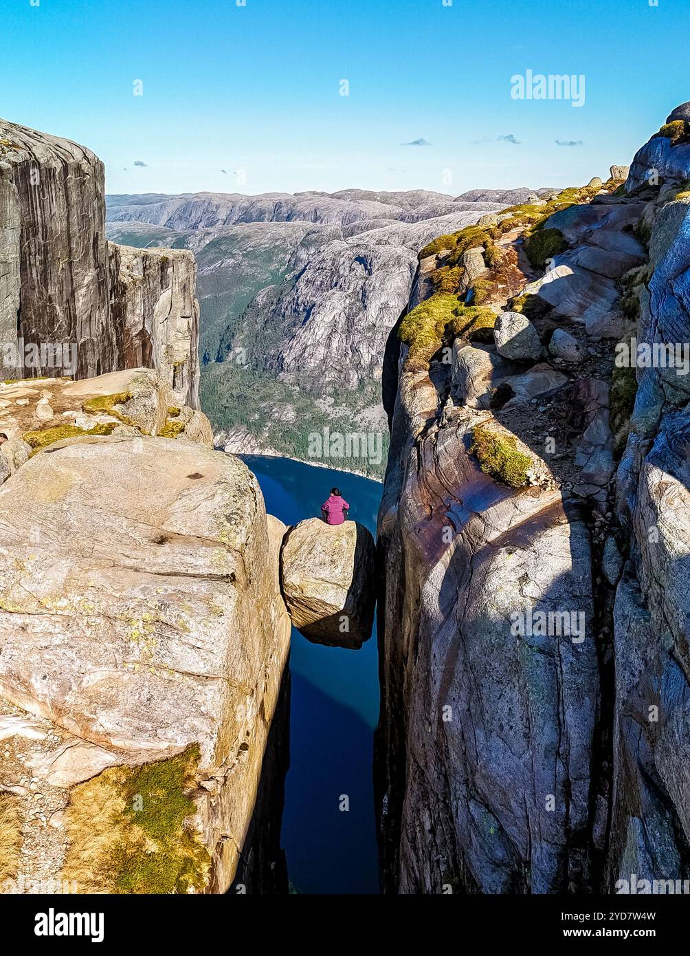 A lone figure sits on the edge of Kjeragbolten, a famous cliff in ...