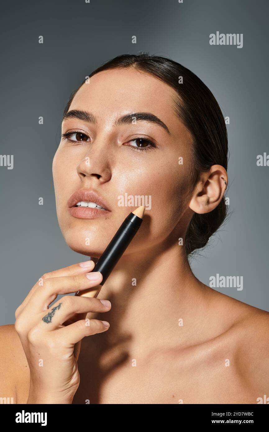 A graceful woman enhances her beauty using a makeup stick while posing ...
