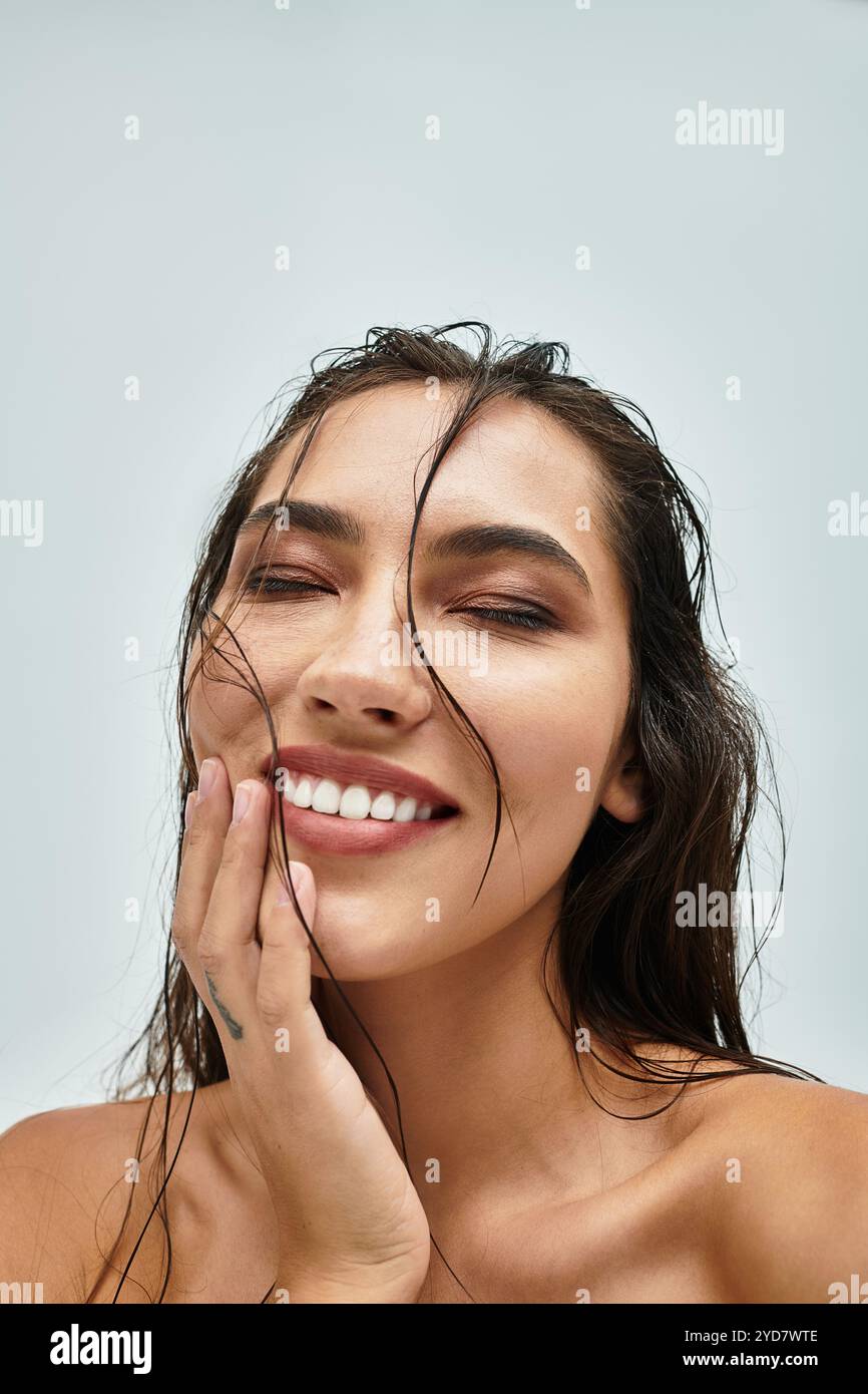 A smiling woman radiates happiness with her hand gently touching her ...