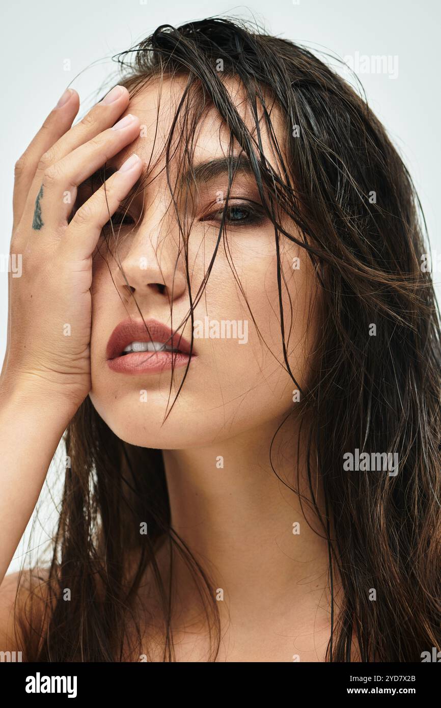A stunning woman poses elegantly, her wet hair framing her striking ...