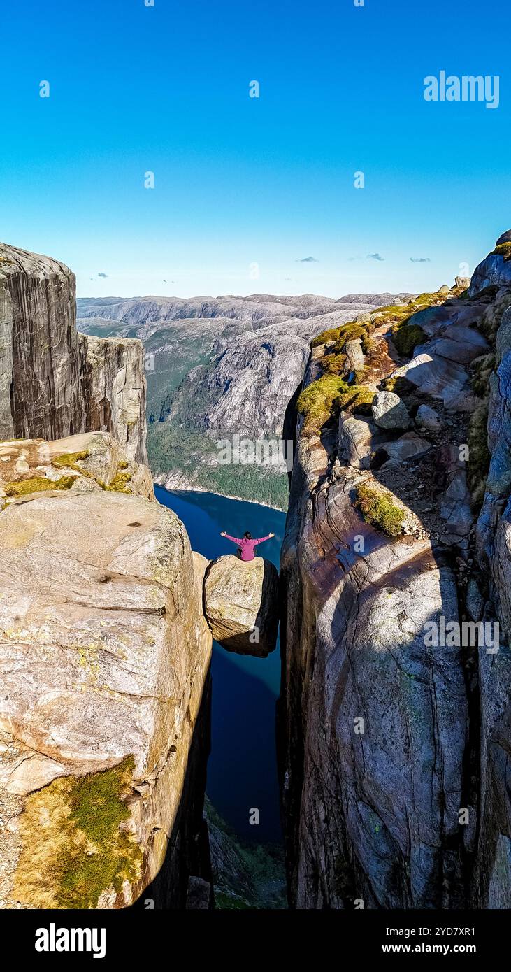 A person stands on the edge of the Kjeragbolten Pulpit Rock in Norway ...