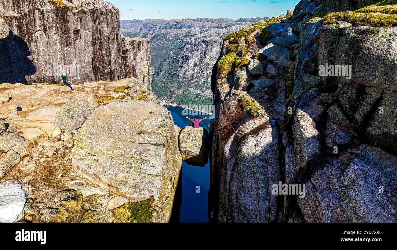 A hiker sits on the edge of Kjeragbolten, also known as the Pulpit Rock ...