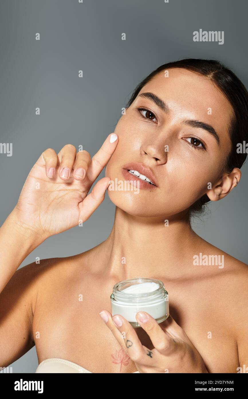 The woman gently applies cream to her face, showcasing her beauty and ...