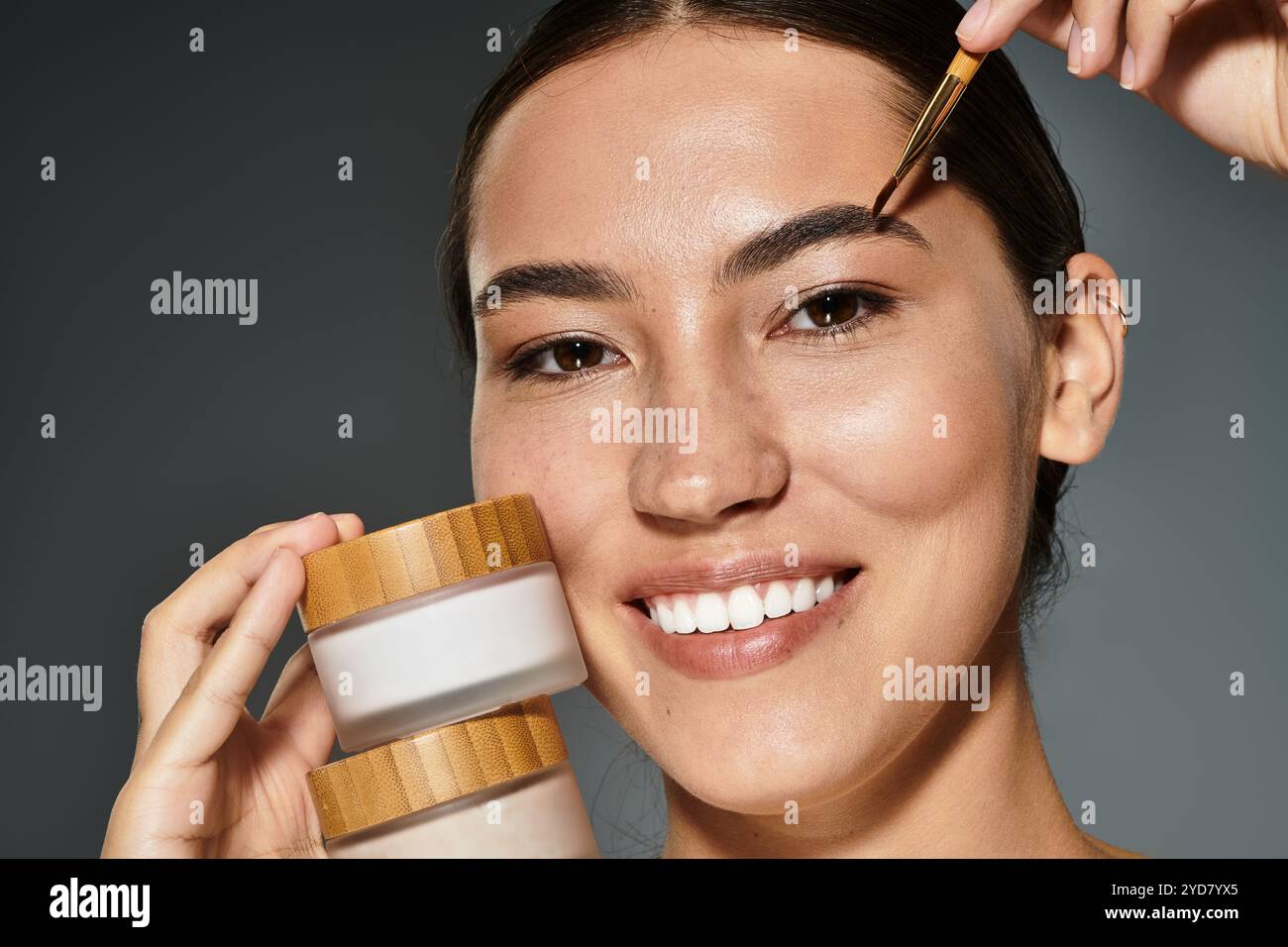 The woman showcases her radiant skin while applying a skincare product ...