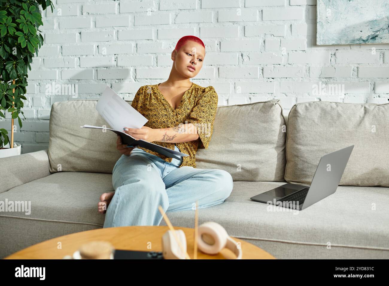 A stylish bald woman relaxes on a couch, reviewing important papers ...