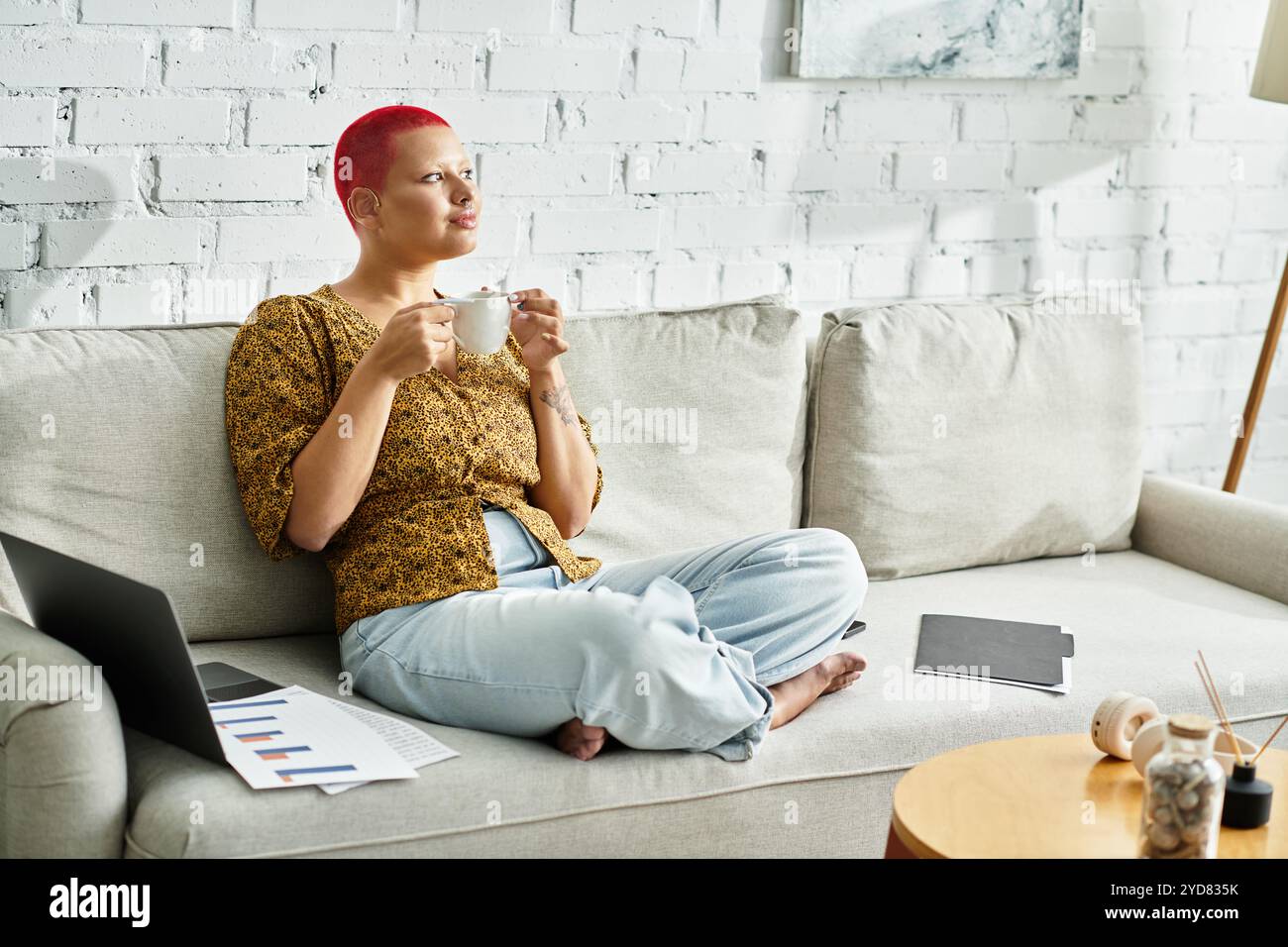 A bald woman savors her coffee while relaxing on a comfortable sofa in ...