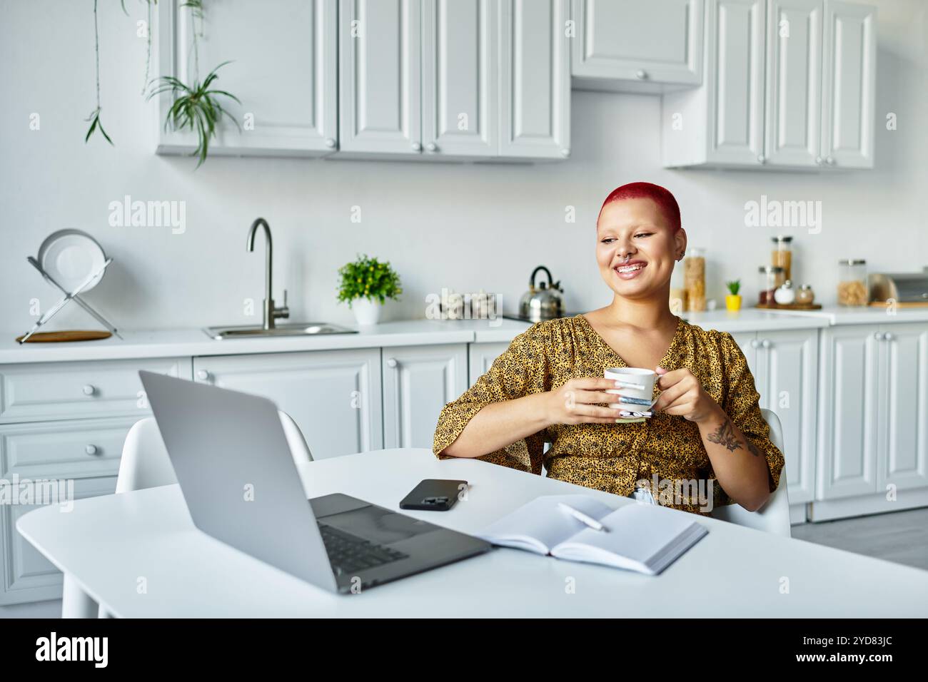 A cheerful bald woman sips her drink while relaxing at a sleek kitchen ...