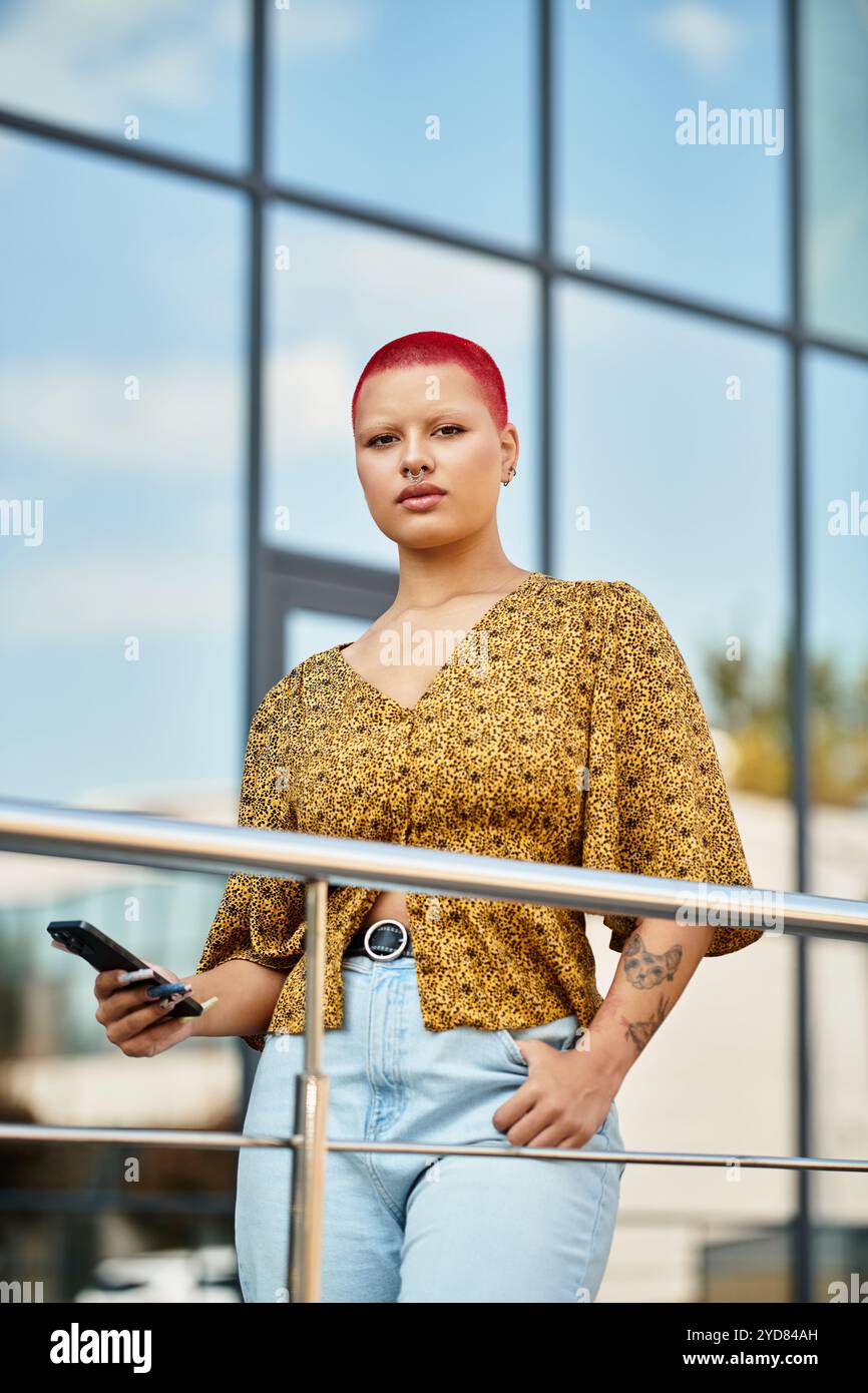 The beautiful bald woman poses confidently on a balcony, holding a ...