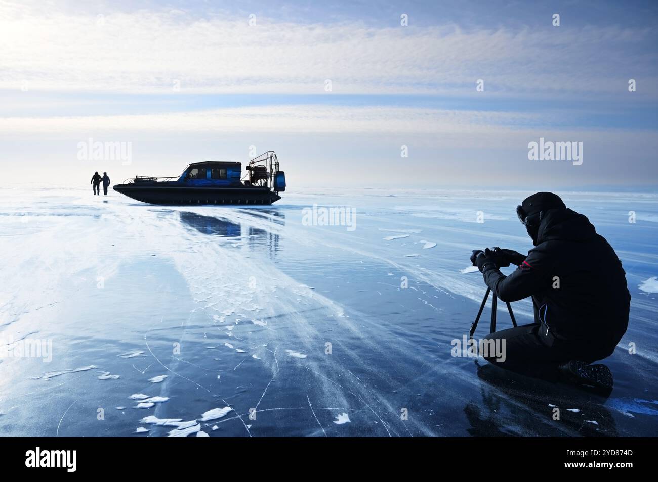 Photographer takes pictures on the clear blue ice of the frozen Lake ...