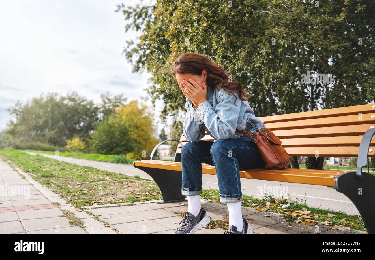 Woman sits on the bench covers face with her hands and crying. Hopeless ...