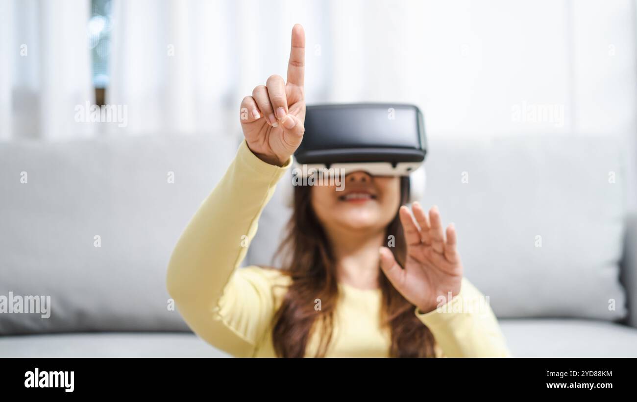 Young Asian woman wearing virtual reality touching air during the VR ...