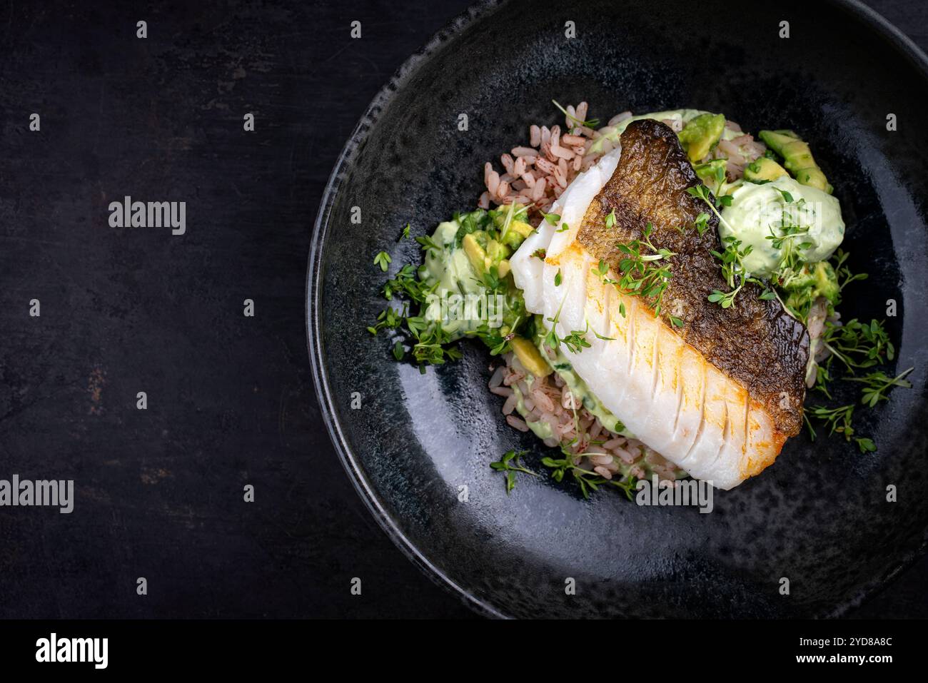 Fried skrei cod fish filet with avocado cream and boiled rice served as ...