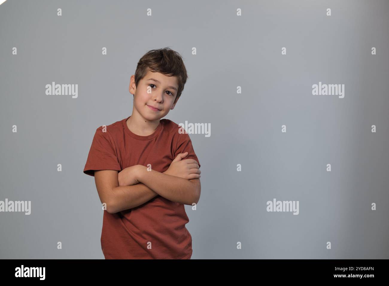 A boy stands with crossed arms, expression serious. His stance speaks ...