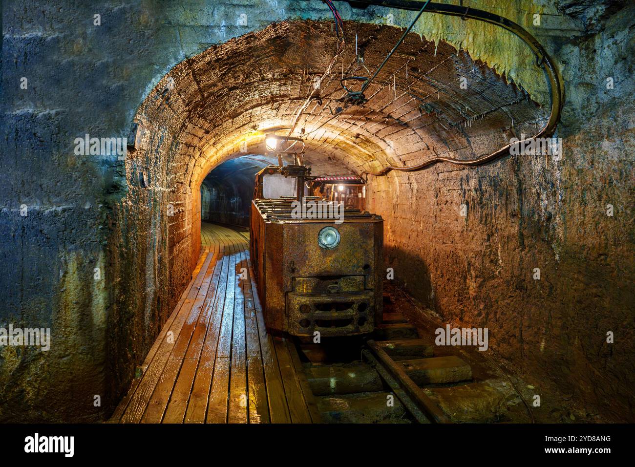 Rusty mining train in a dark tunnel under the mountain with tracks and ...