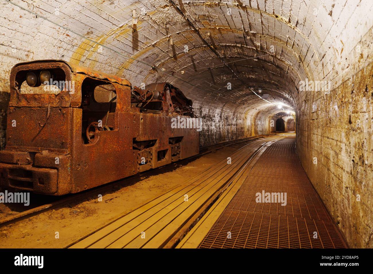 Old rusty mining train in a dark tunnel with tracks in the foreground ...