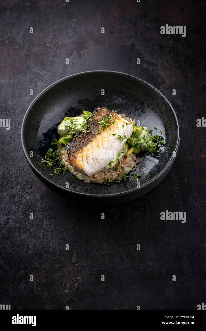 Fried skrei cod fish filet with avocado cream and boiled rice served as ...