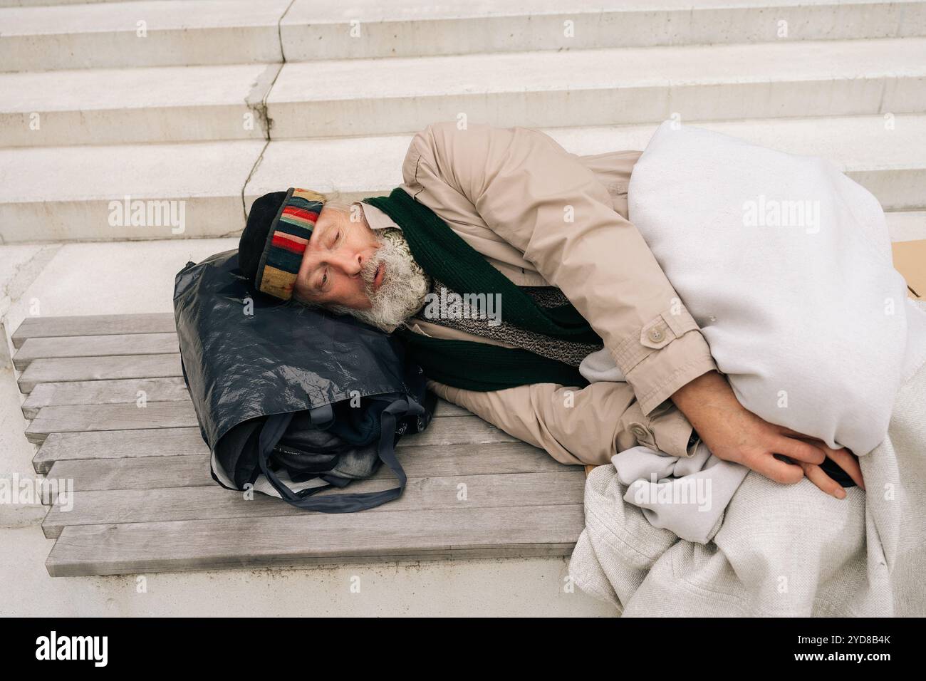 Portrait of freezing elderly homeless man sleeping on urban bench ...