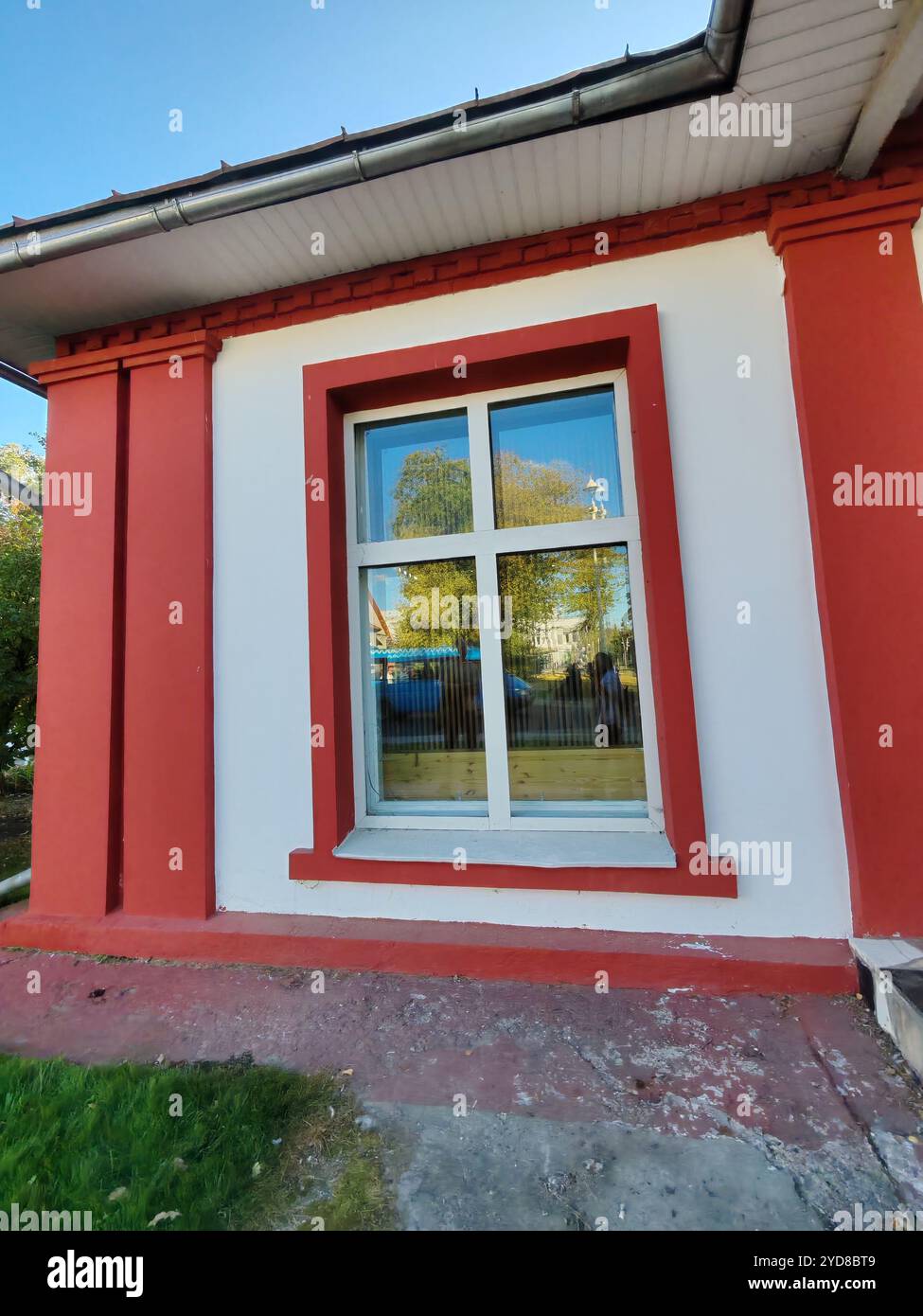 A building with a red-bordered window set in a white wall, reflecting ...