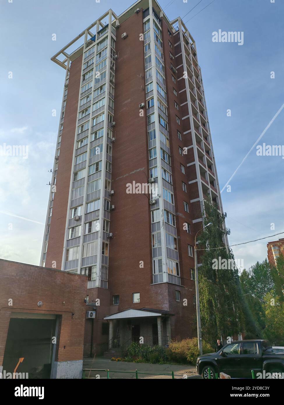 A tall red and beige brick residential building with multiple balconies ...