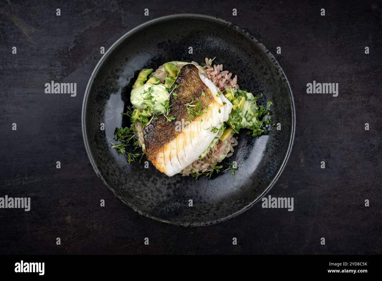 Fried skrei cod fish filet with avocado cream and boiled rice served as ...