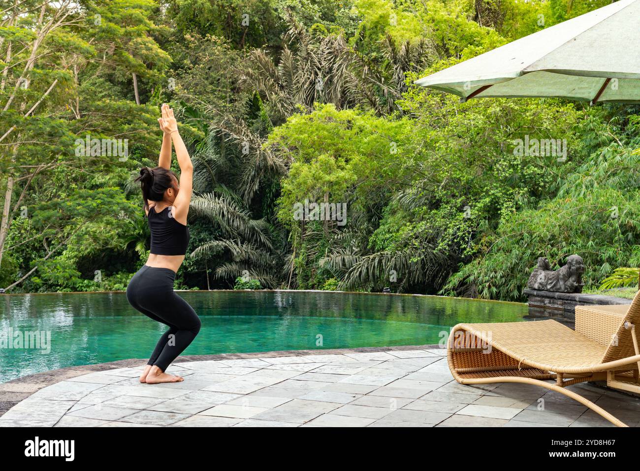 A woman practicing yoga outdoors in a lush green environment. She is in ...