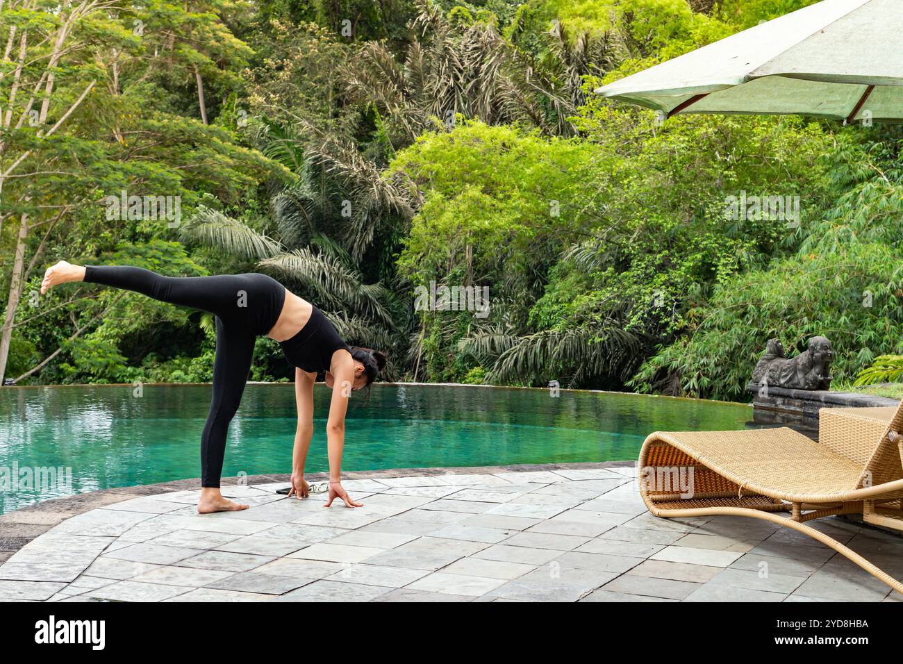 A woman practicing yoga outdoors in a lush green environment. She is in ...