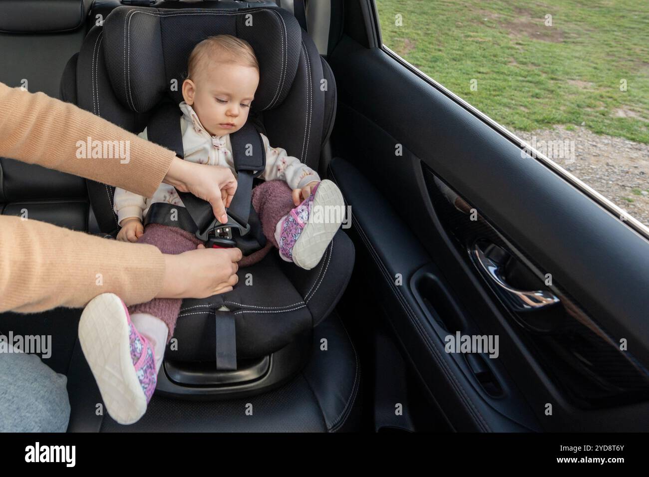 Mother putting baby girl in child seat in the car. Getting ready for a ...