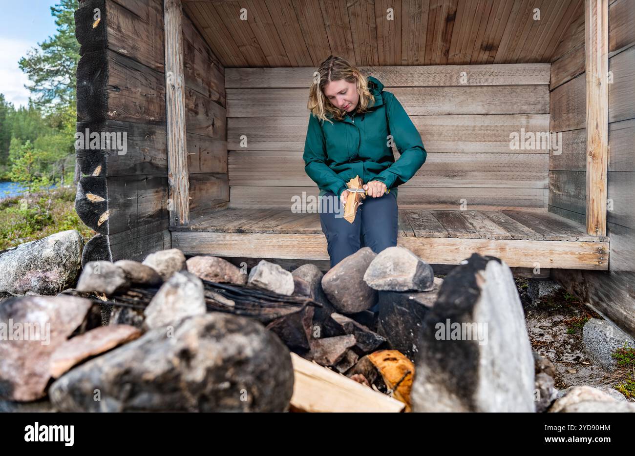 Outdoor woman sitting in a log shelter hut (slogbod) in the Swedish ...