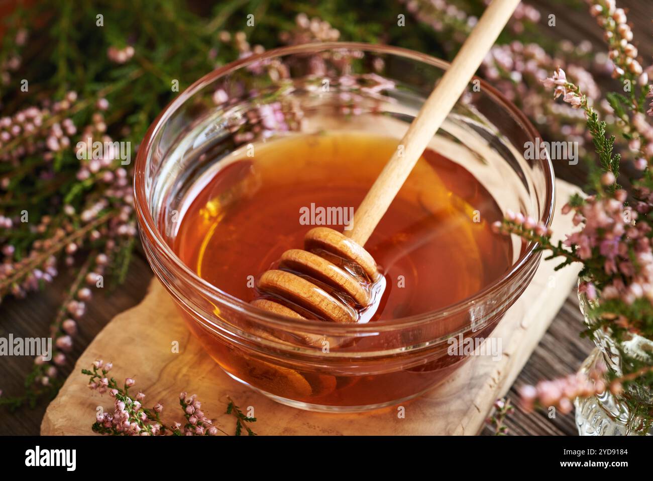 Herbal syrup in a glass bowl with fresh wild heather flowers harvested ...