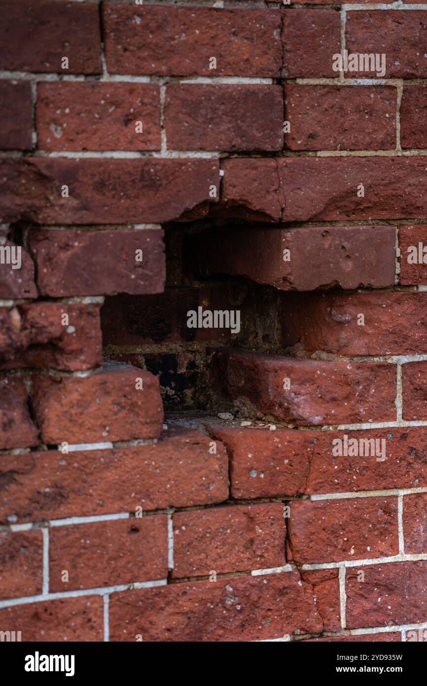 A hole in the red brick wall. A cross in a brick wall The dilapidated ...
