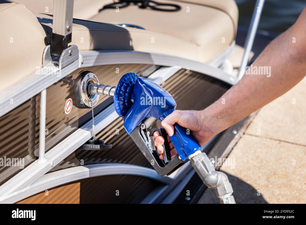 Man refueling boat at marina. Gas pump nozzle filling pontoon party ...