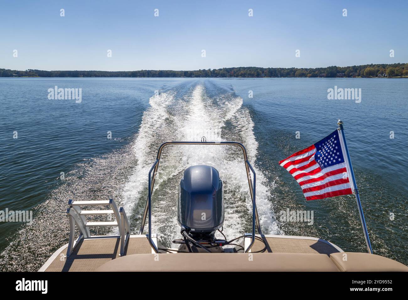 Boat wake behind boat on freshwater lake. American flag flying behind ...