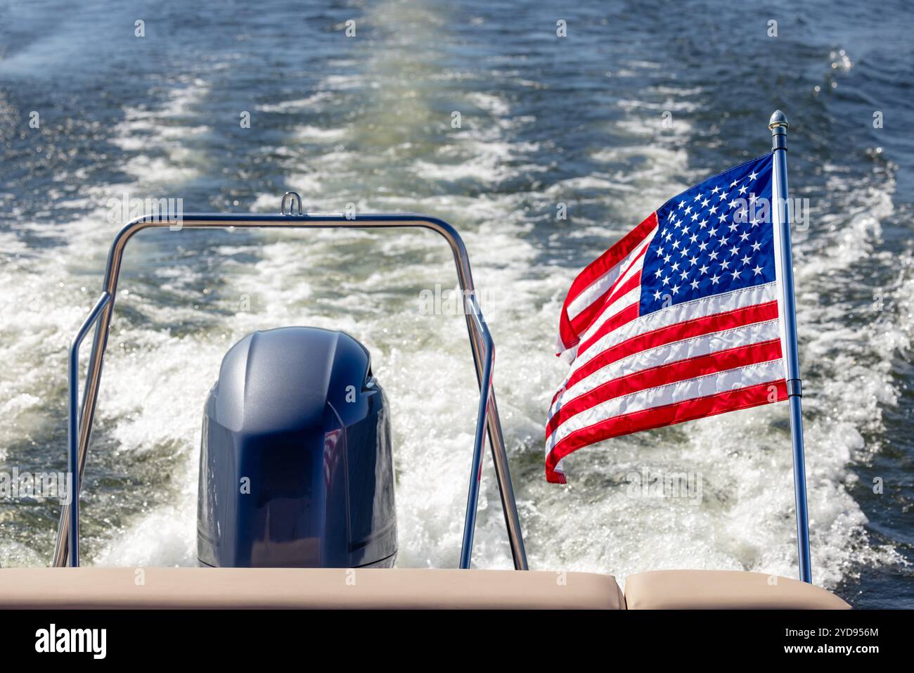 American flag flying behind pontoon party boat. Boat wake behind boat ...
