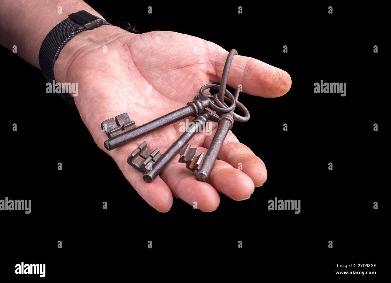 Antique rusty iron keys in the palm of a man on a black background ...