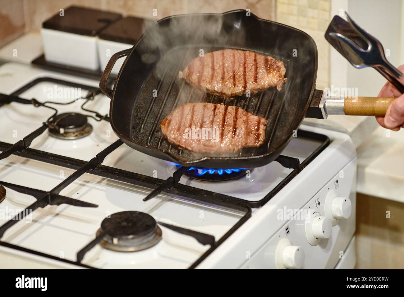 The process of cooking two beef steaks in frying pan, the hands of male ...