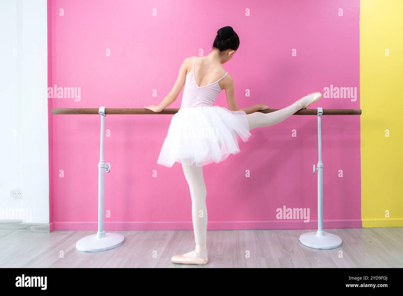 A girl ballet student practices ballet dancing at home with a pink and ...