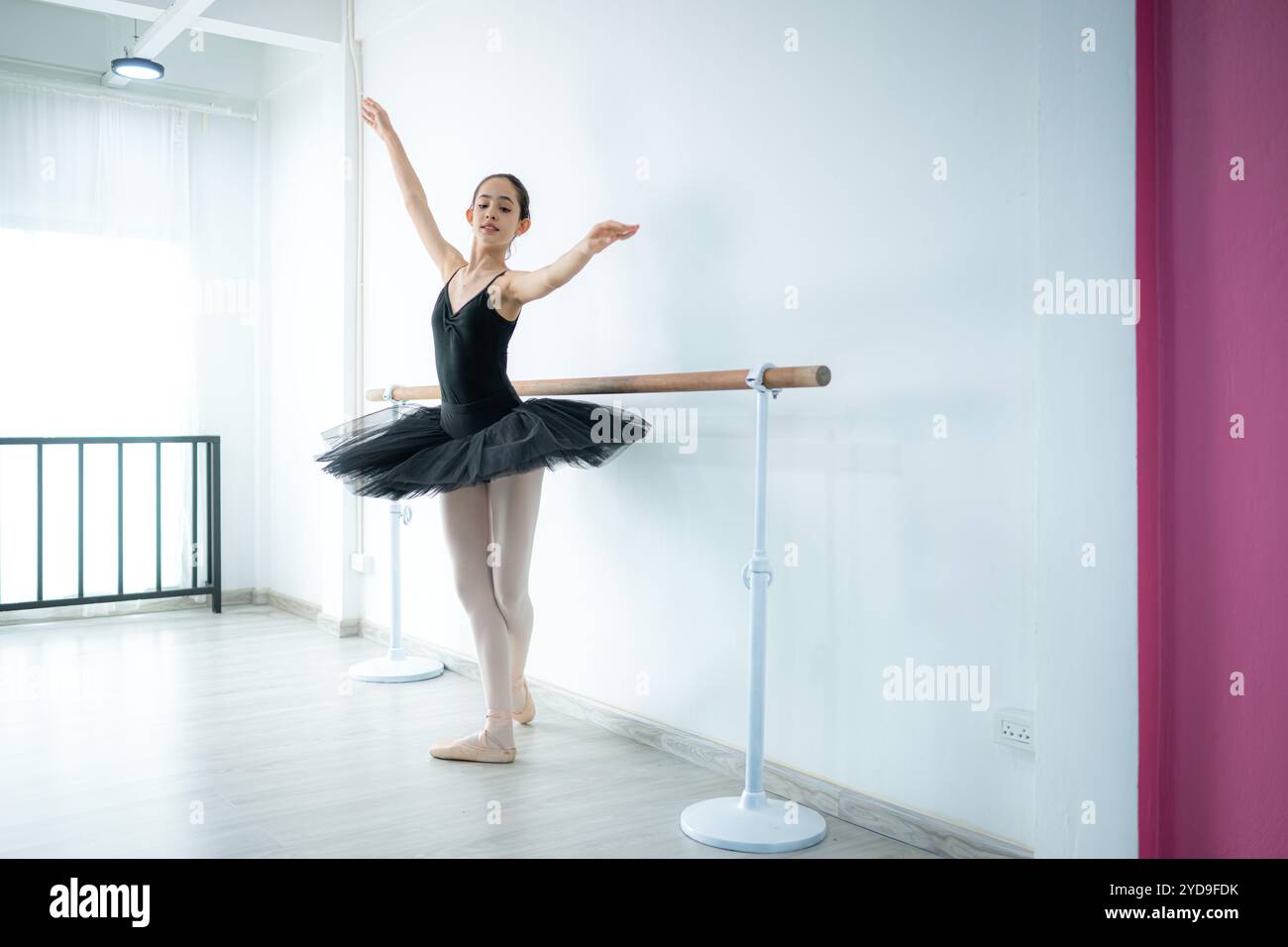 A girl ballet student practices ballet dancing at home with a white ...