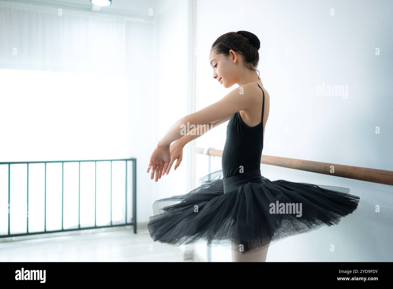 A girl ballet student practices ballet dancing at home with a white ...