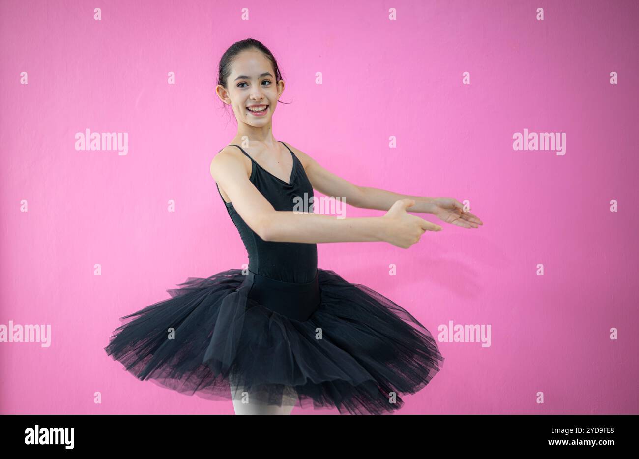 A girl ballet student practices ballet dancing at home with a white ...