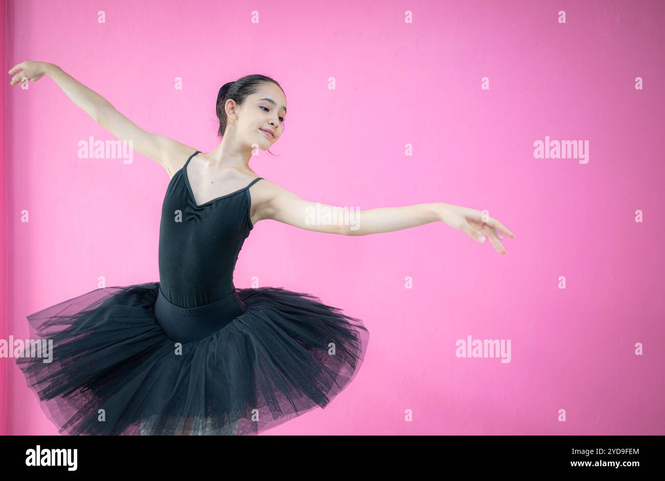 A girl ballet student practices ballet dancing at home with a white ...