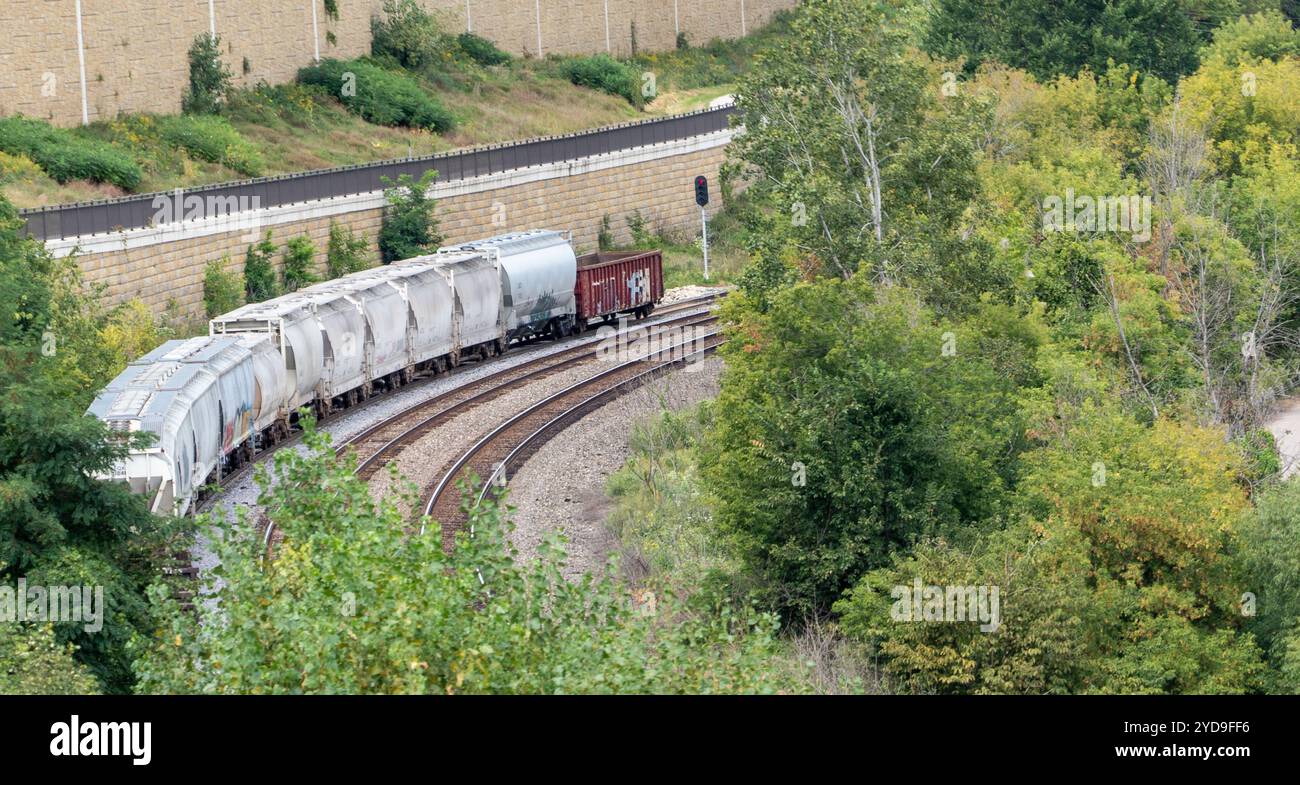 Train is traveling down a track with a green hill in the background ...