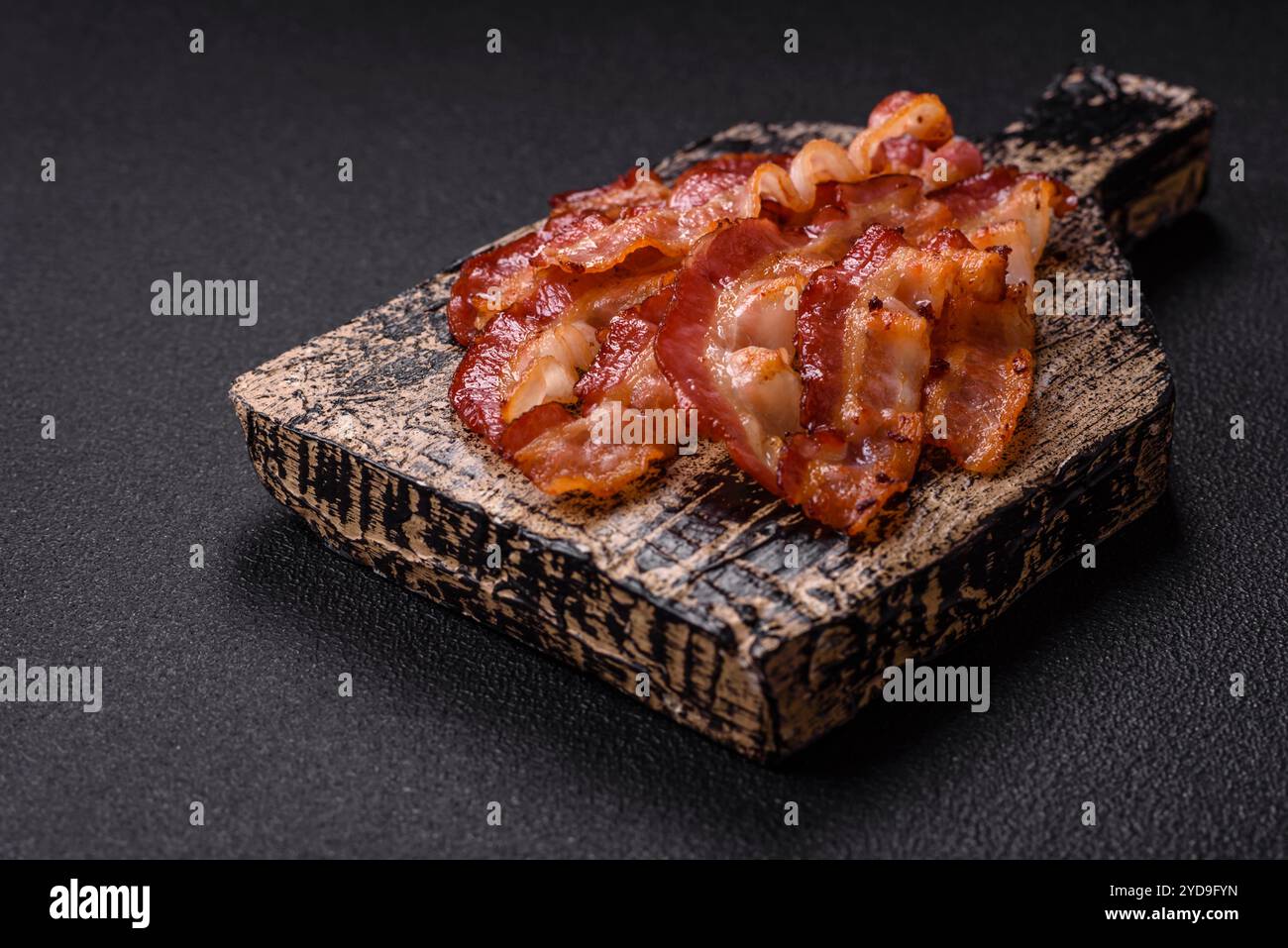Delicious fresh fried bacon with salt and spices on a dark background ...