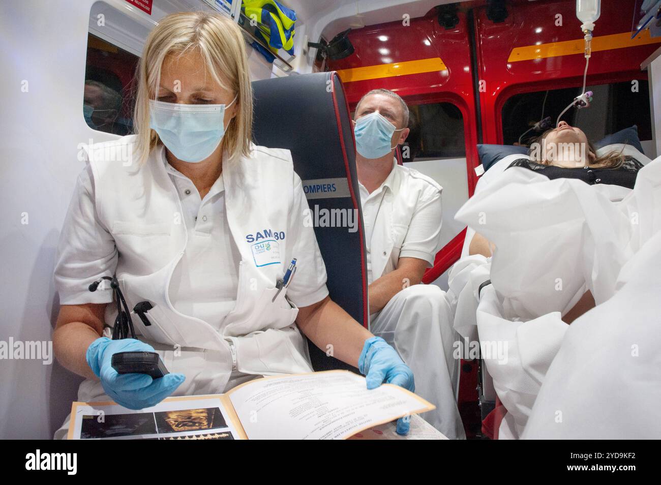 A paramedic and medical team attending to a patient in an ambulance ...
